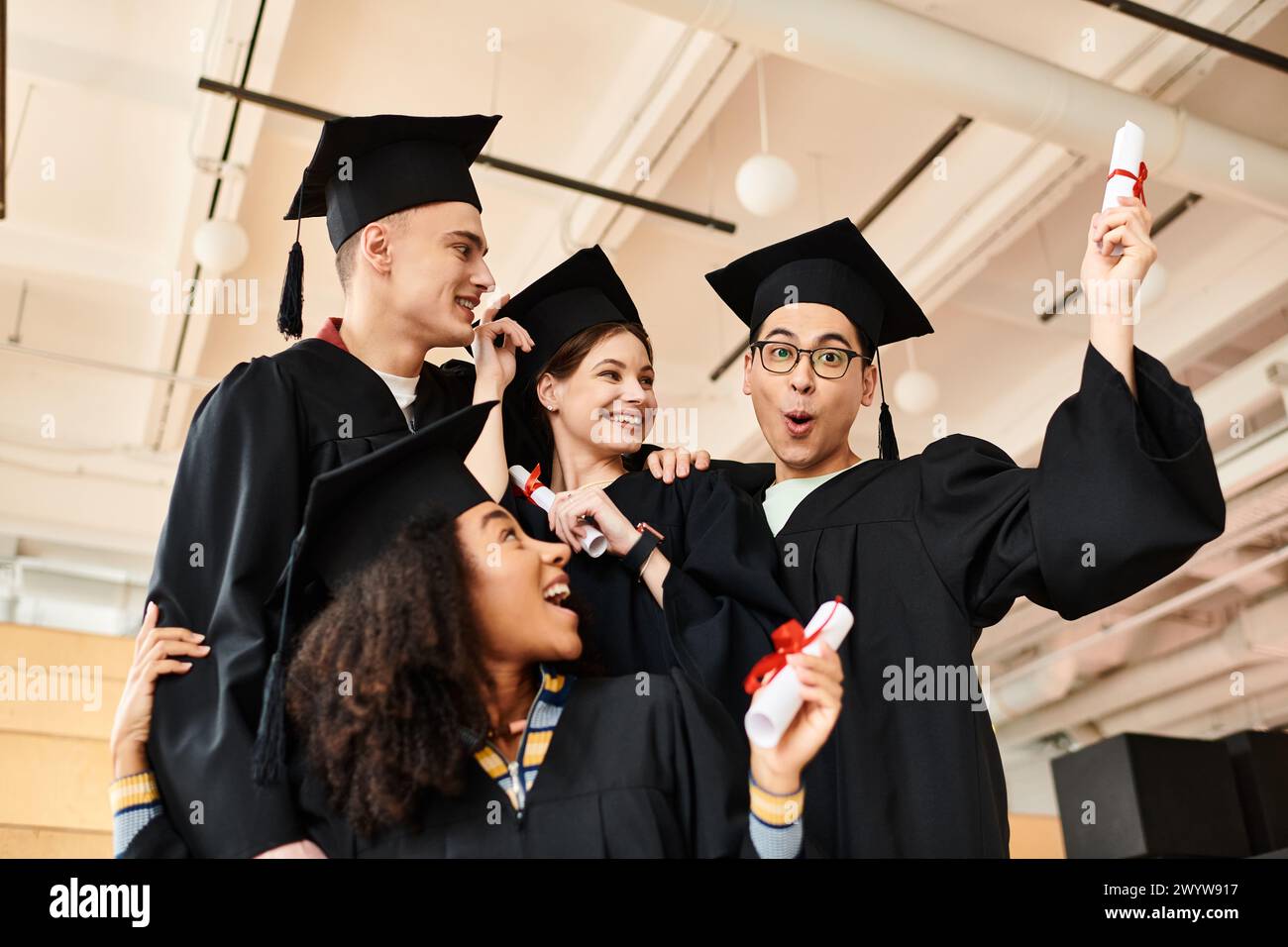 Diverse group of students in graduation gowns and caps happily taking a ...