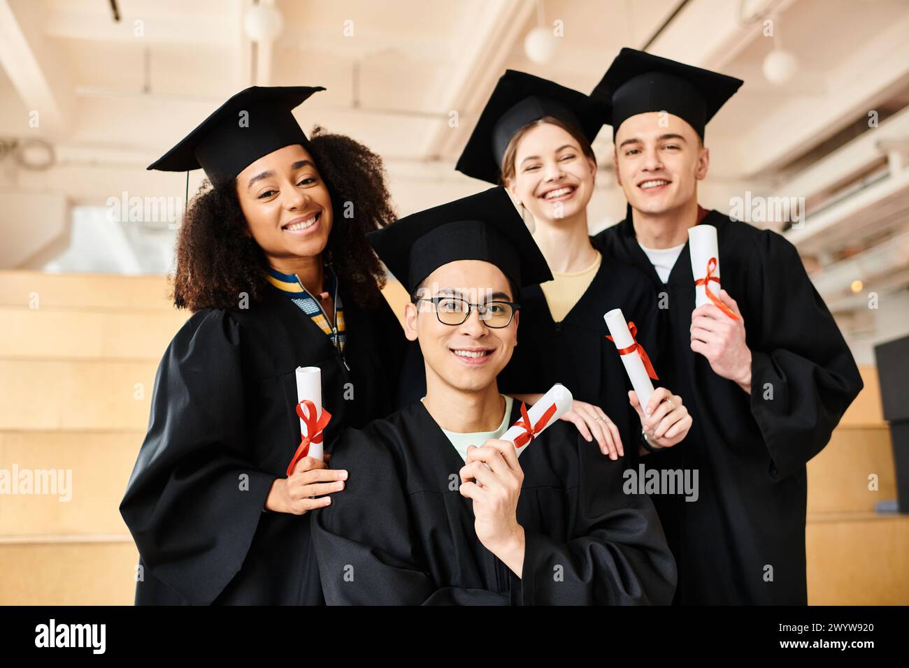 Diverse group in graduation gowns happily holding diplomas Stock Photo ...