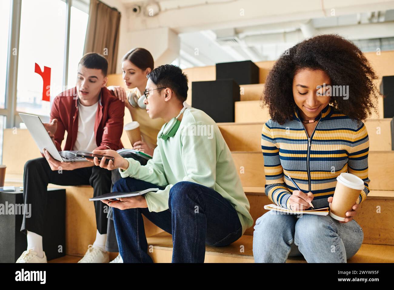 Multicultural group of students engage in group work on laptops while ...