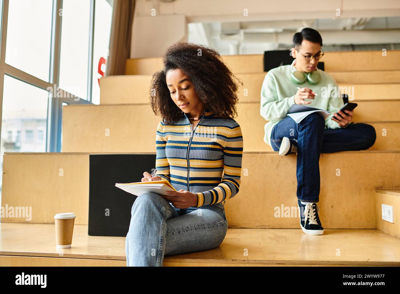 Two people, a multicultural pair, sitting on the steps of a building ...