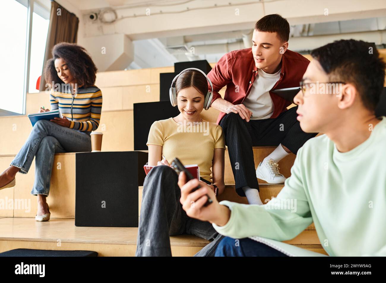 A multicultural group of students sit comfortably on a modern staircase ...
