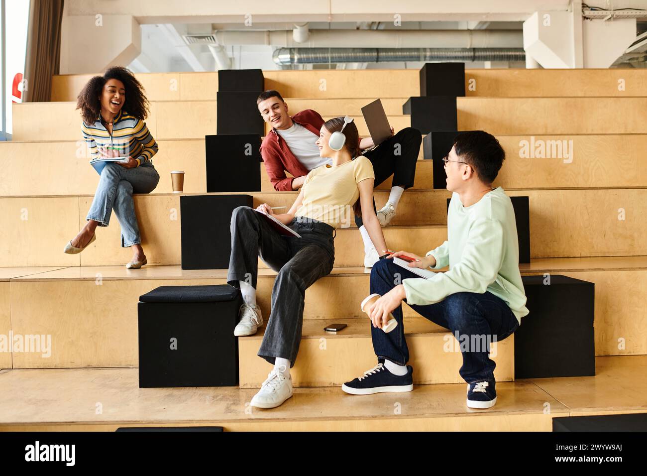 Multicultural students of varying backgrounds sit on a staircase ...