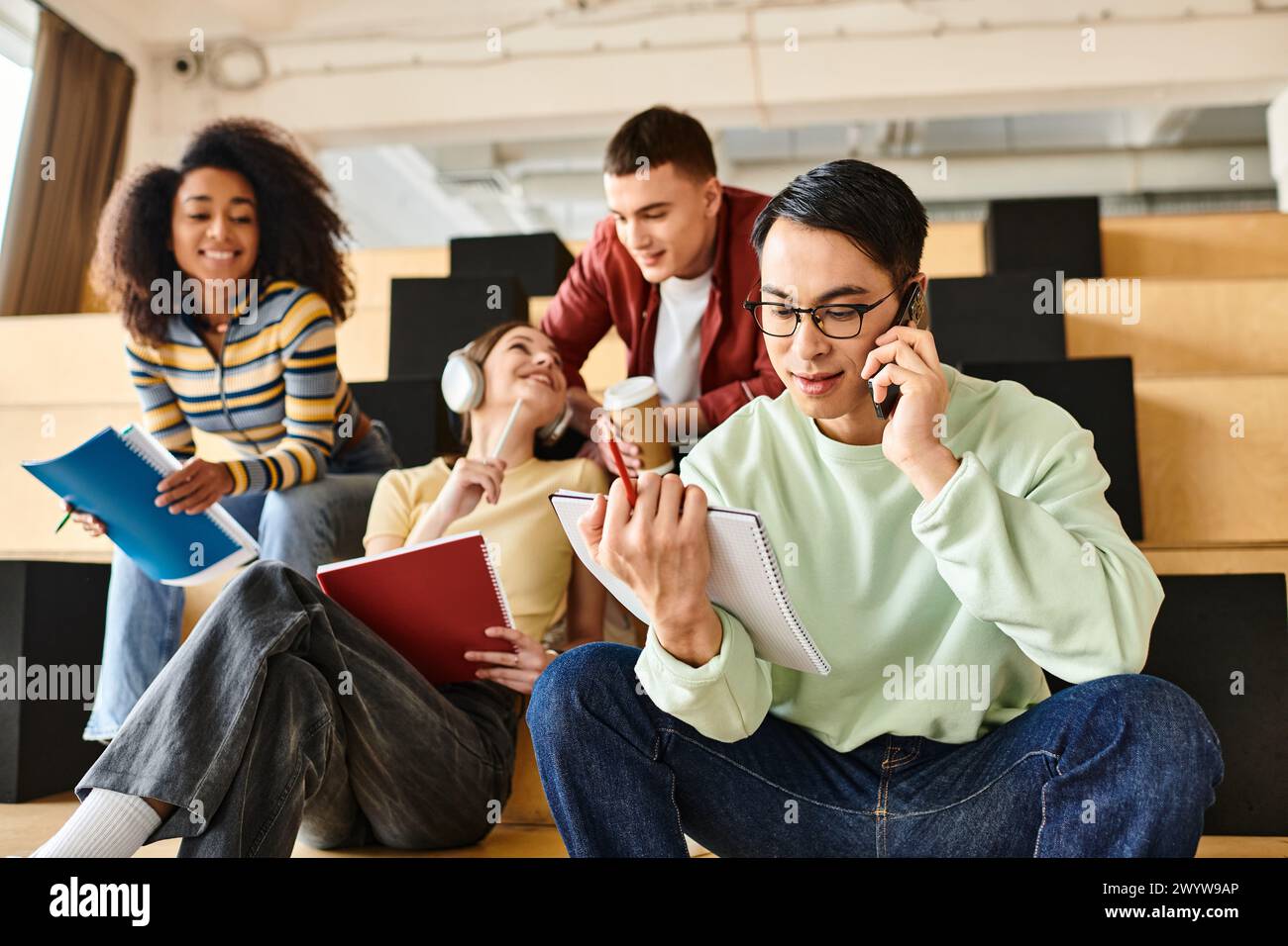 Multicultural students sit on the floor, absorbed in phone ...