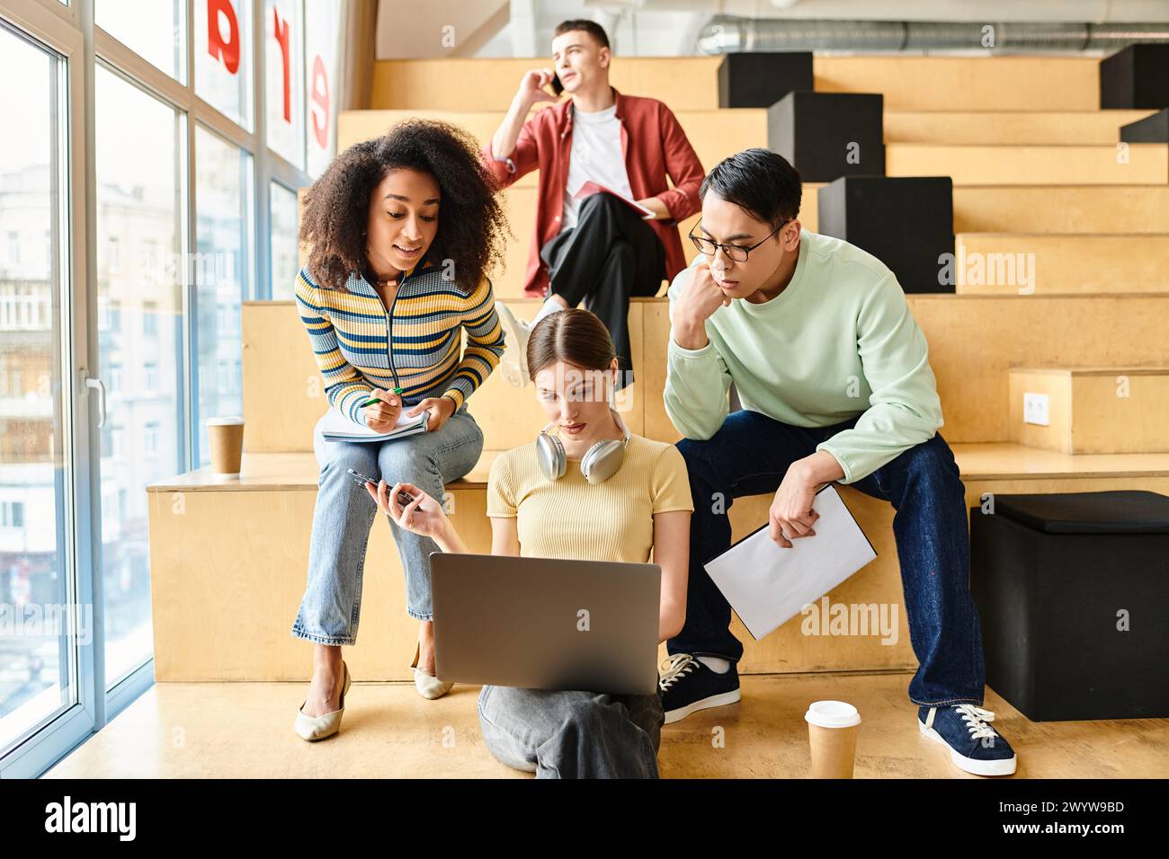 Multicultural students collaborate around a laptop computer, engaging ...