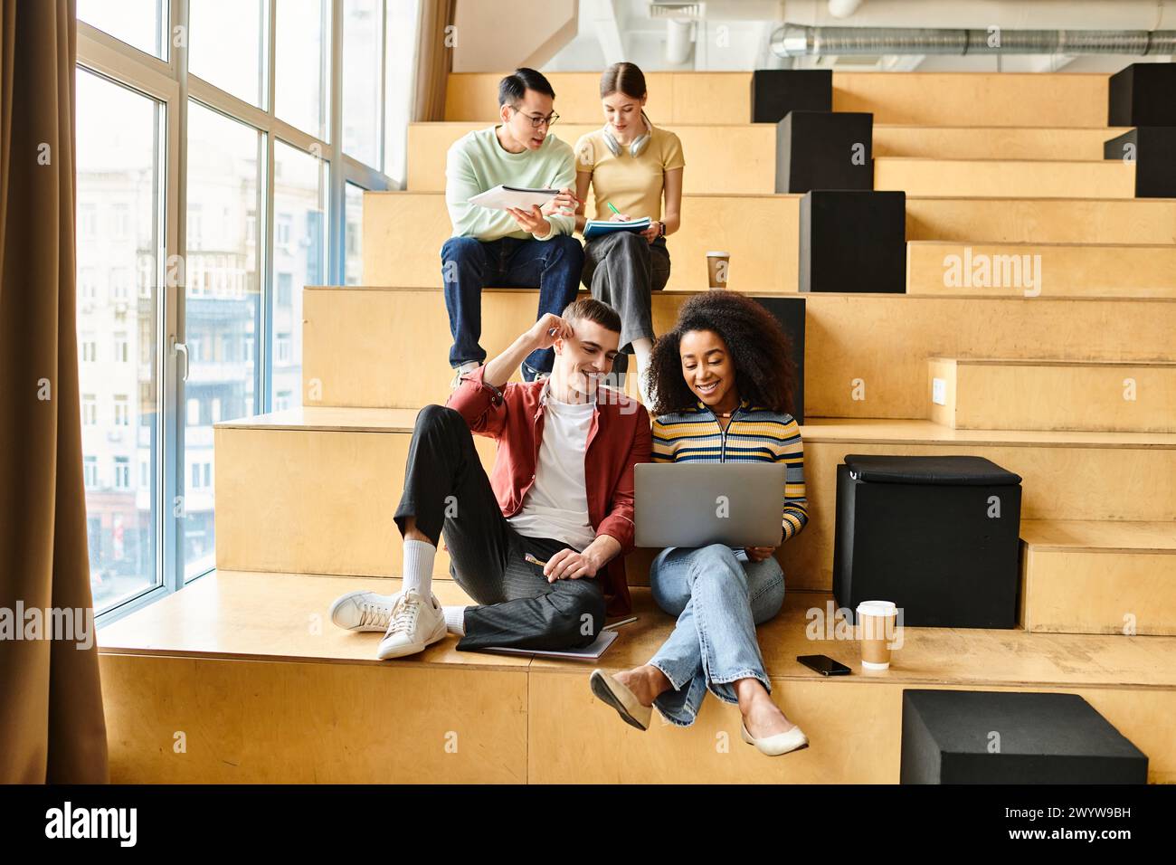 Multicultural students relax on steps of a modern building, chatting ...