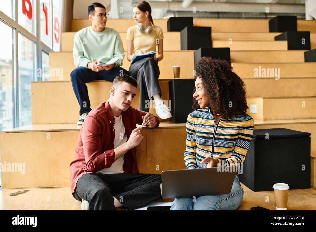 A multicultural group of students sitting around a laptop, engaged in ...