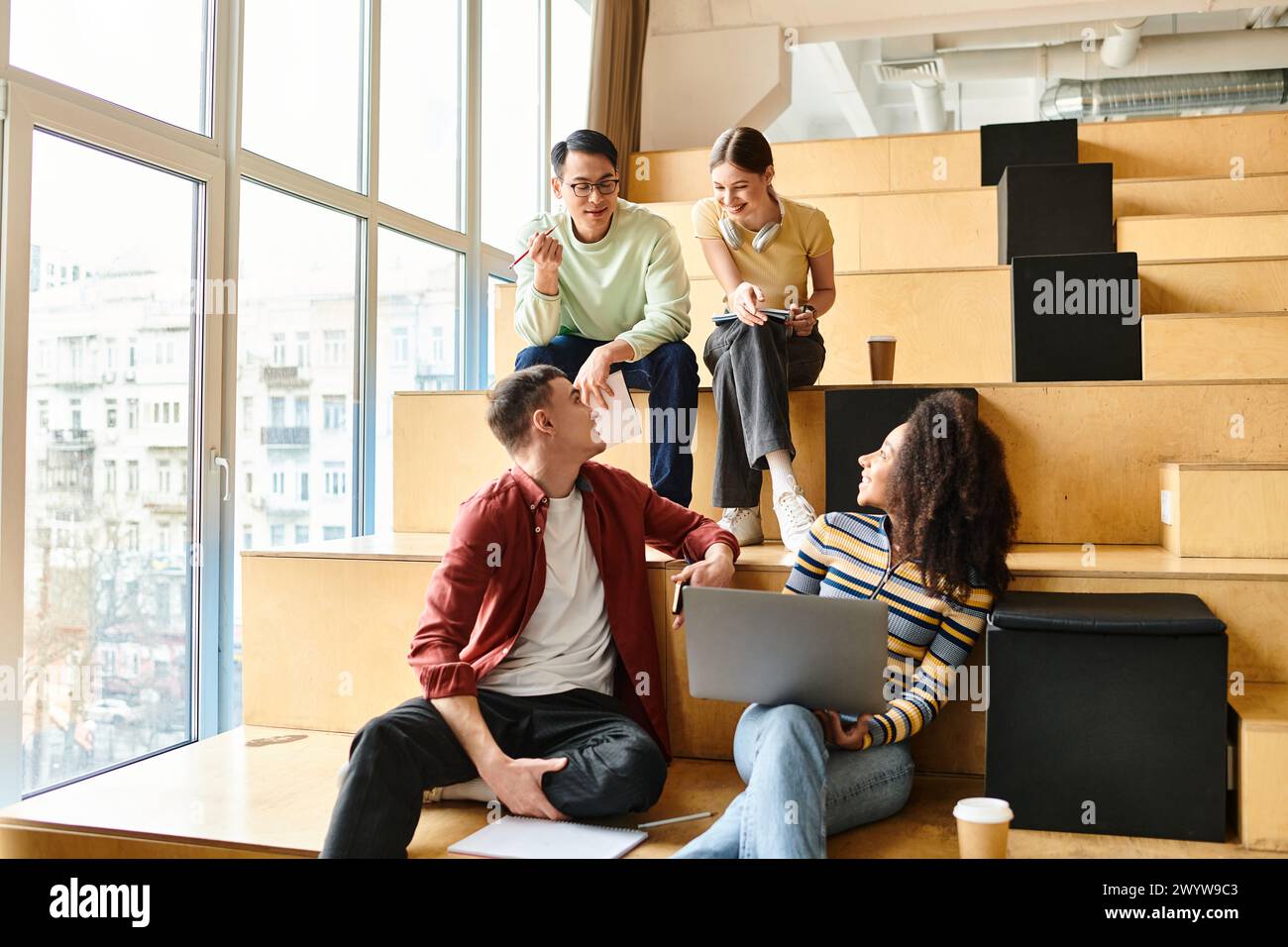 A multicultural group of students sit on the steps of a brick building ...