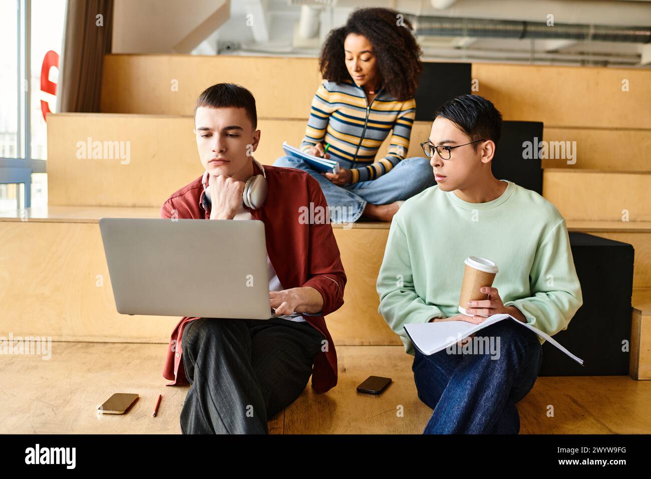 Multicultural group of individuals sitting on stairs, focused on their ...