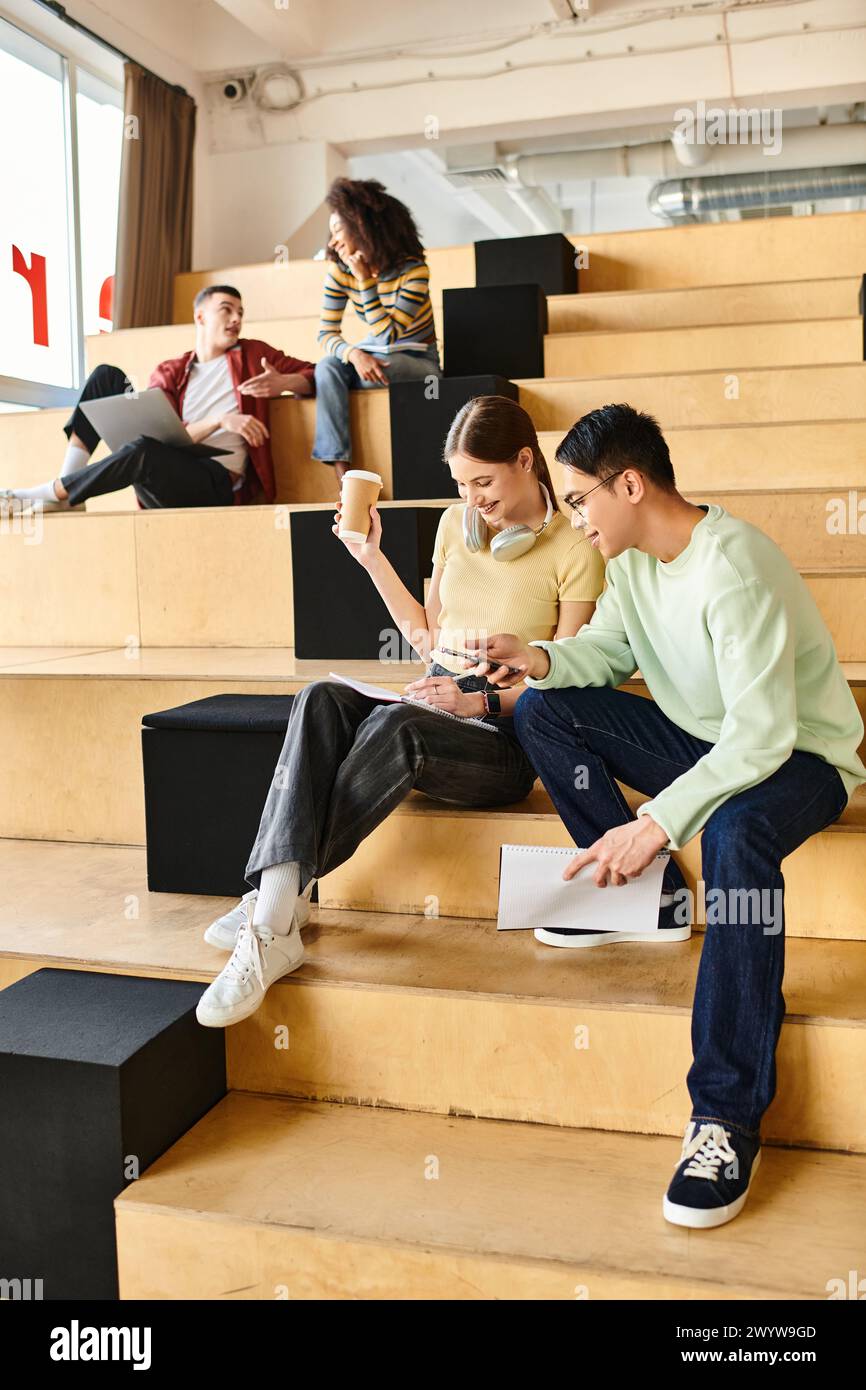Multicultural group of students sitting atop stairs, engaged in ...