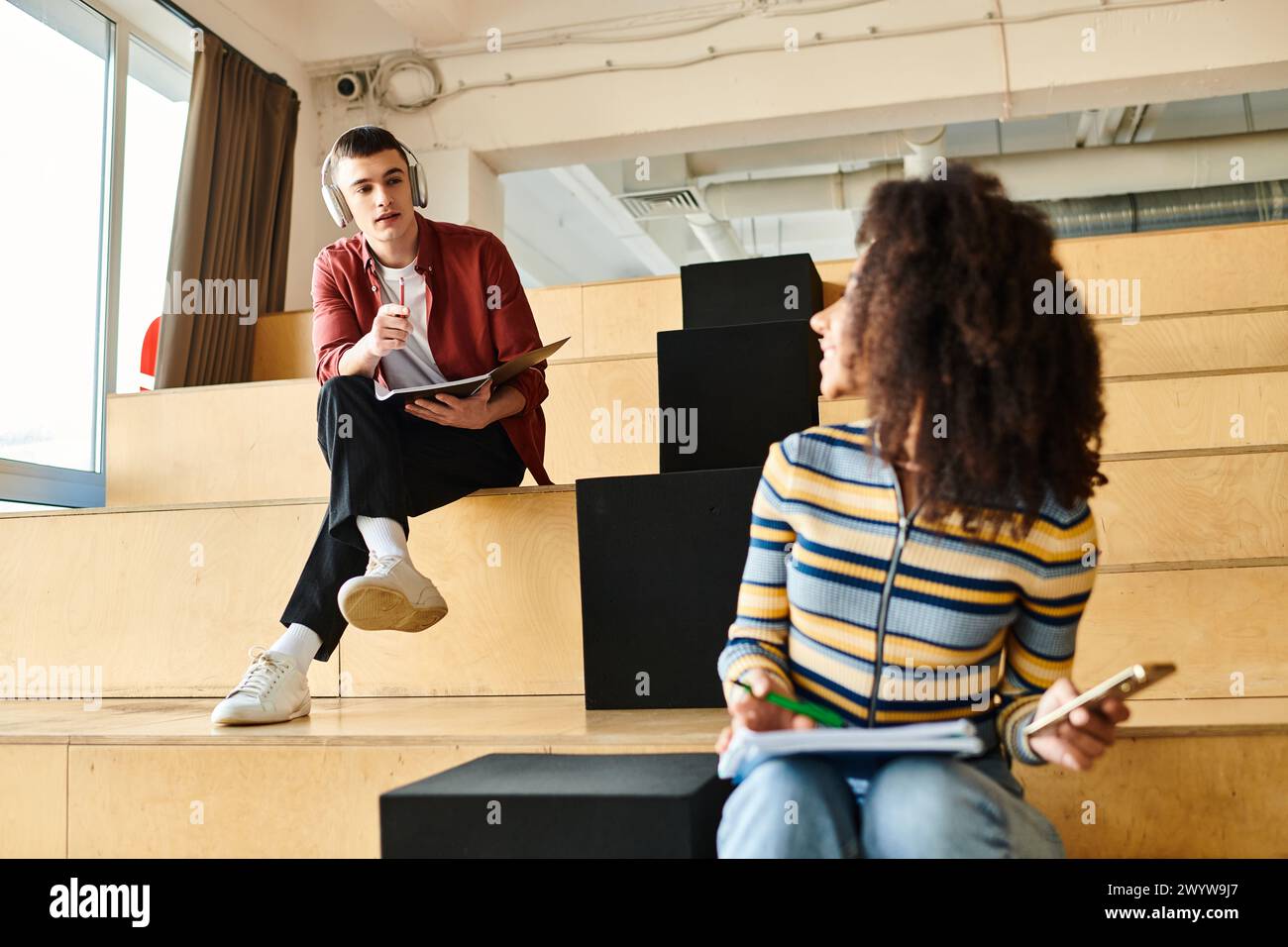 A man and woman, both students, engage in a conversation while seated ...