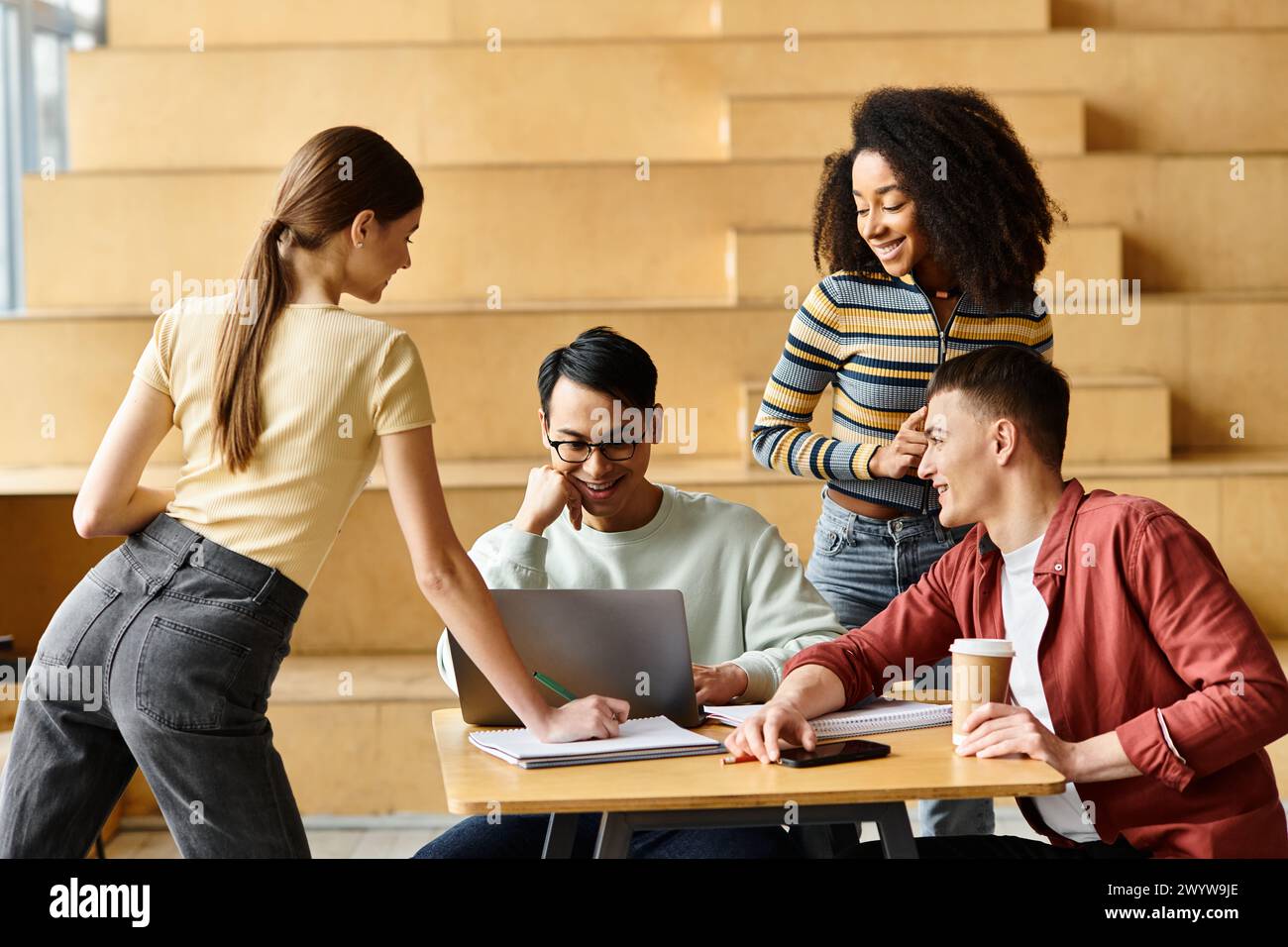 Multicultural group of students happily collaborating around a table ...