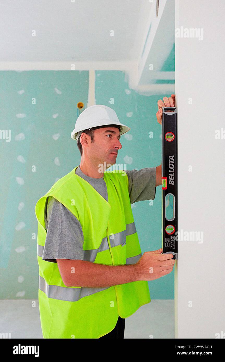 Worker with protective equipment, PPE, Leveling plasterboard panels ...