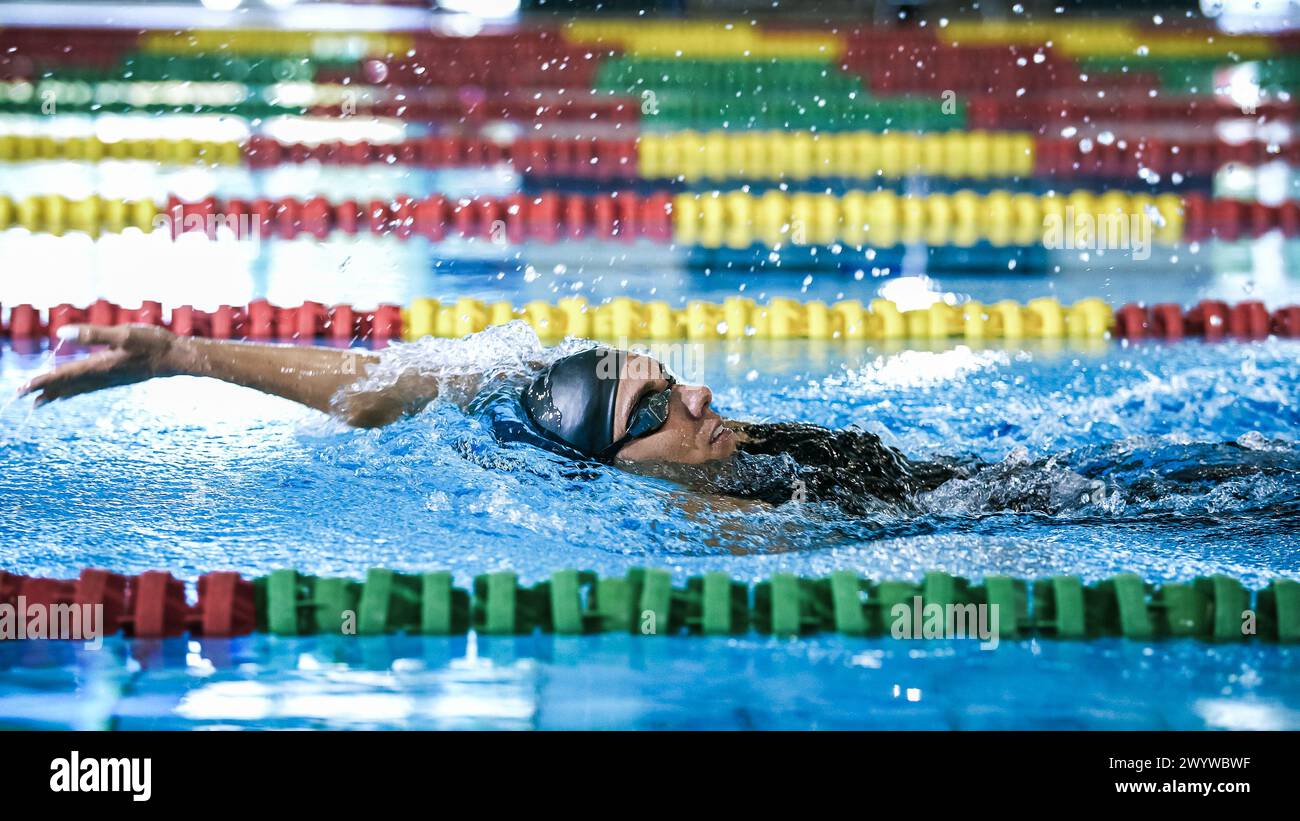 Female athlete in action, performing the backstroke swim technique in ...