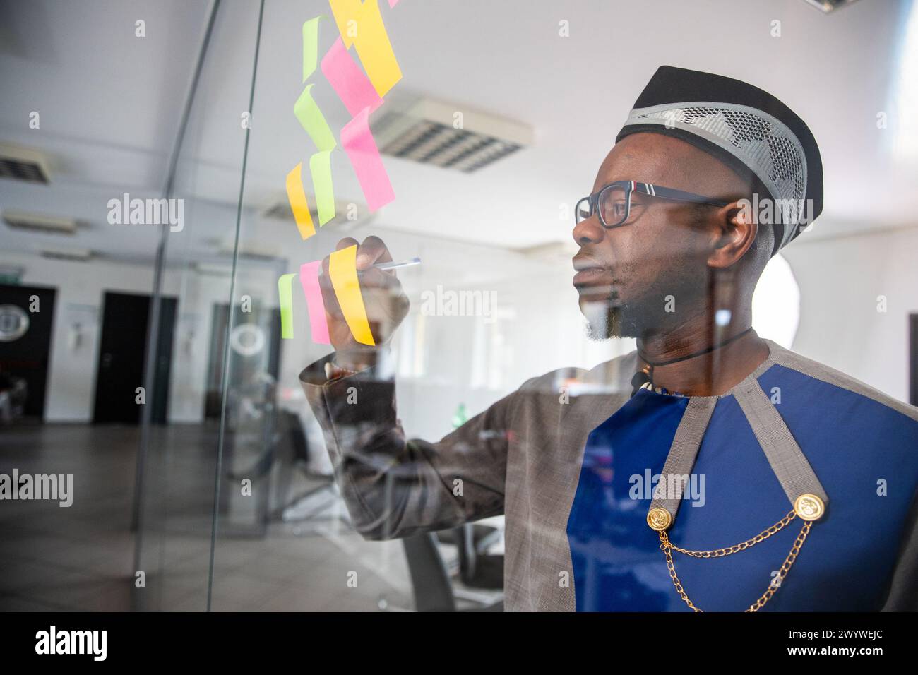 An African businessman writes on colorful sticky notes hanging on the ...