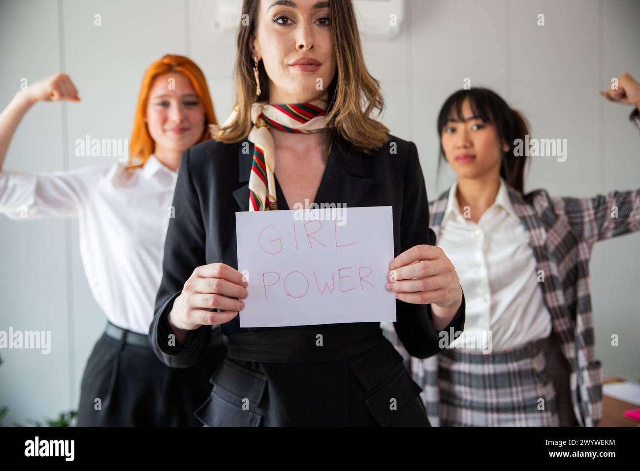 A businesswoman holds a paper with "Girl Power" written on it while her ...