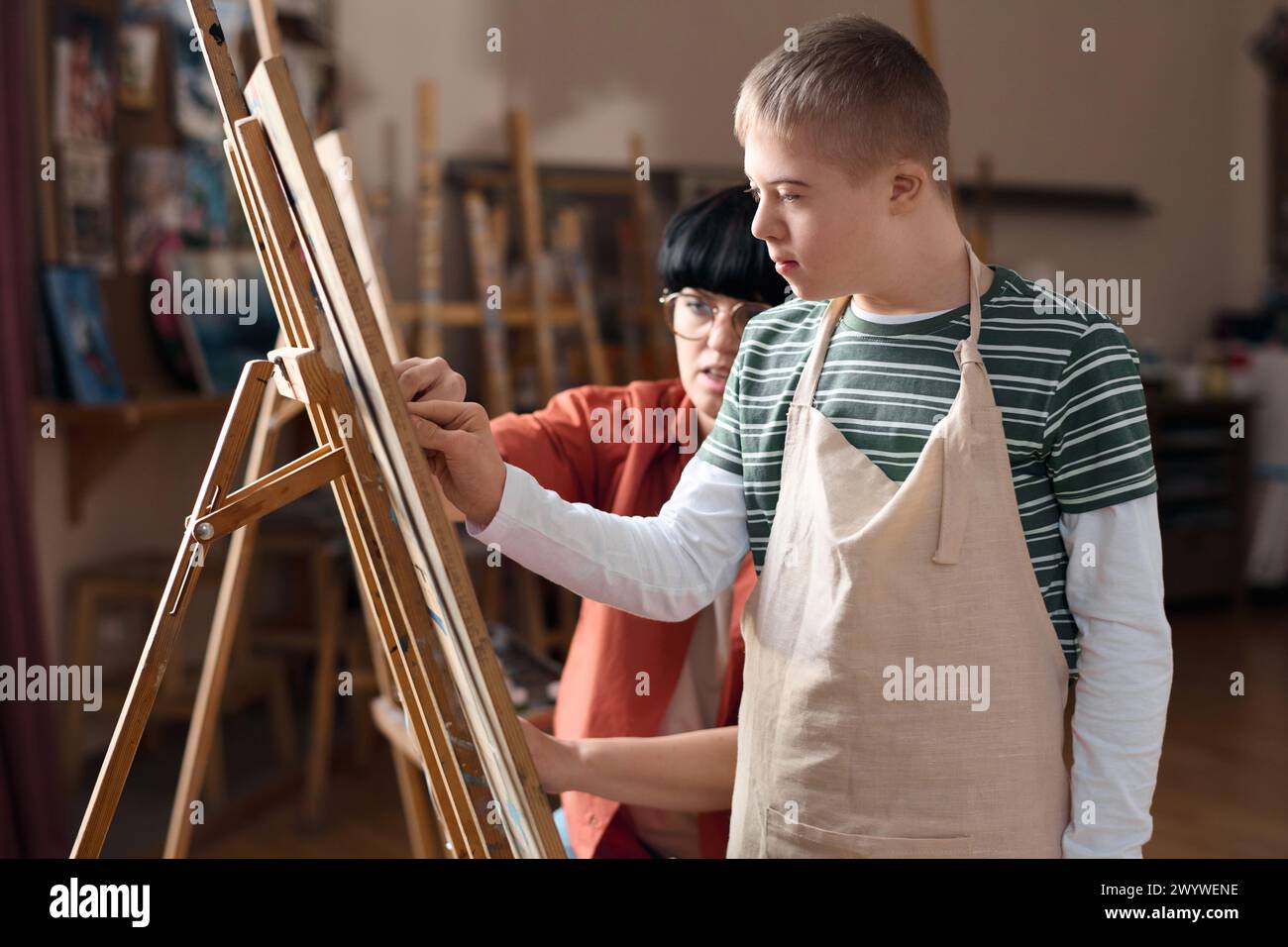 Side view portrait of young boy with disability drawing picture in art ...