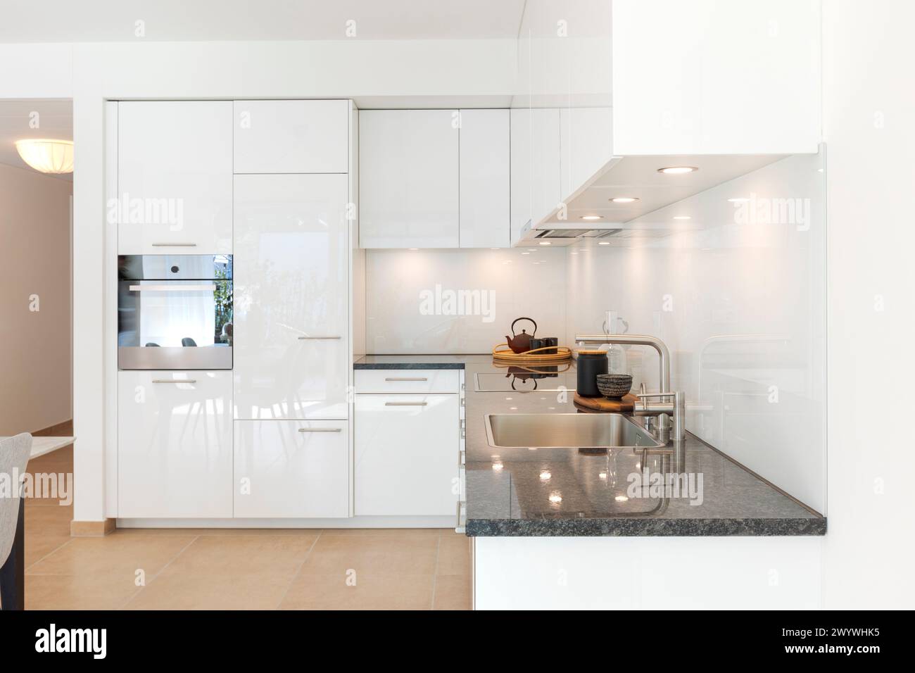 Interior of a new white corner kitchen. You can see the sink and also ...