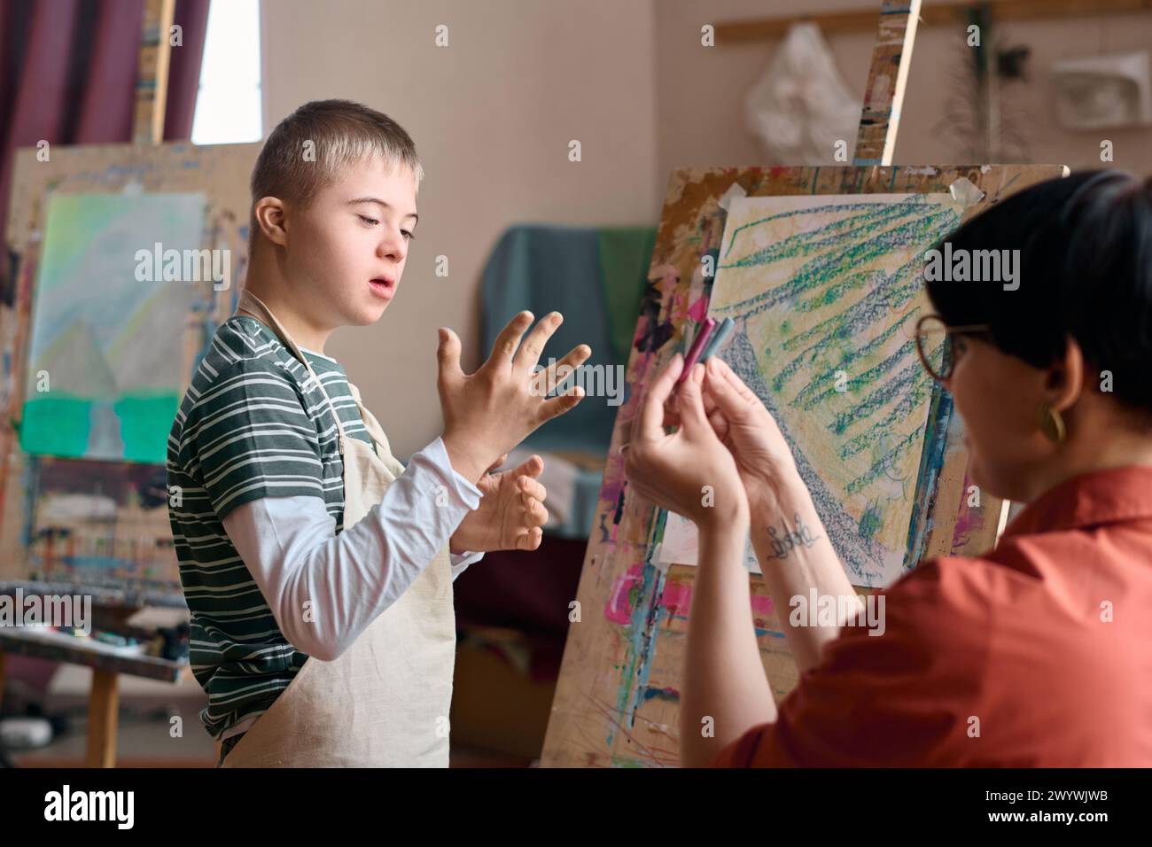 Portrait of young boy with Down syndrome choosing paint colors while ...