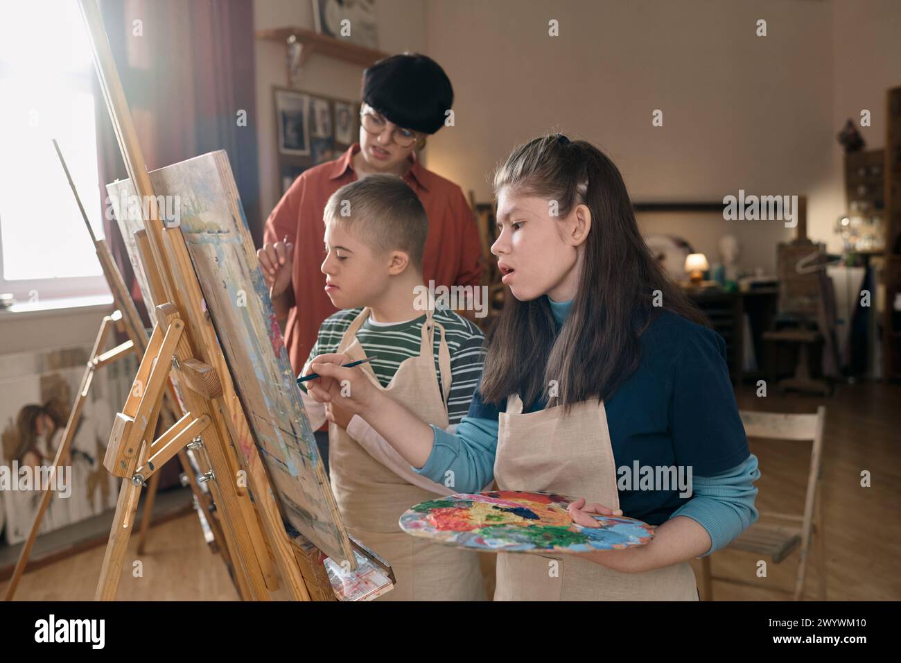 Portrait of two children with disability painting on easels in art ...