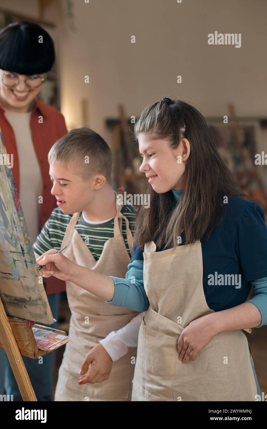Vertical portrait of boy and girl with disability painting together on ...
