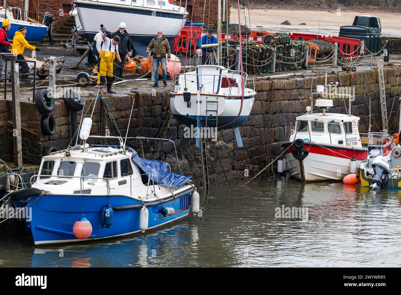 Crane lifting sailing boat into water, North Berwick harbour, East ...