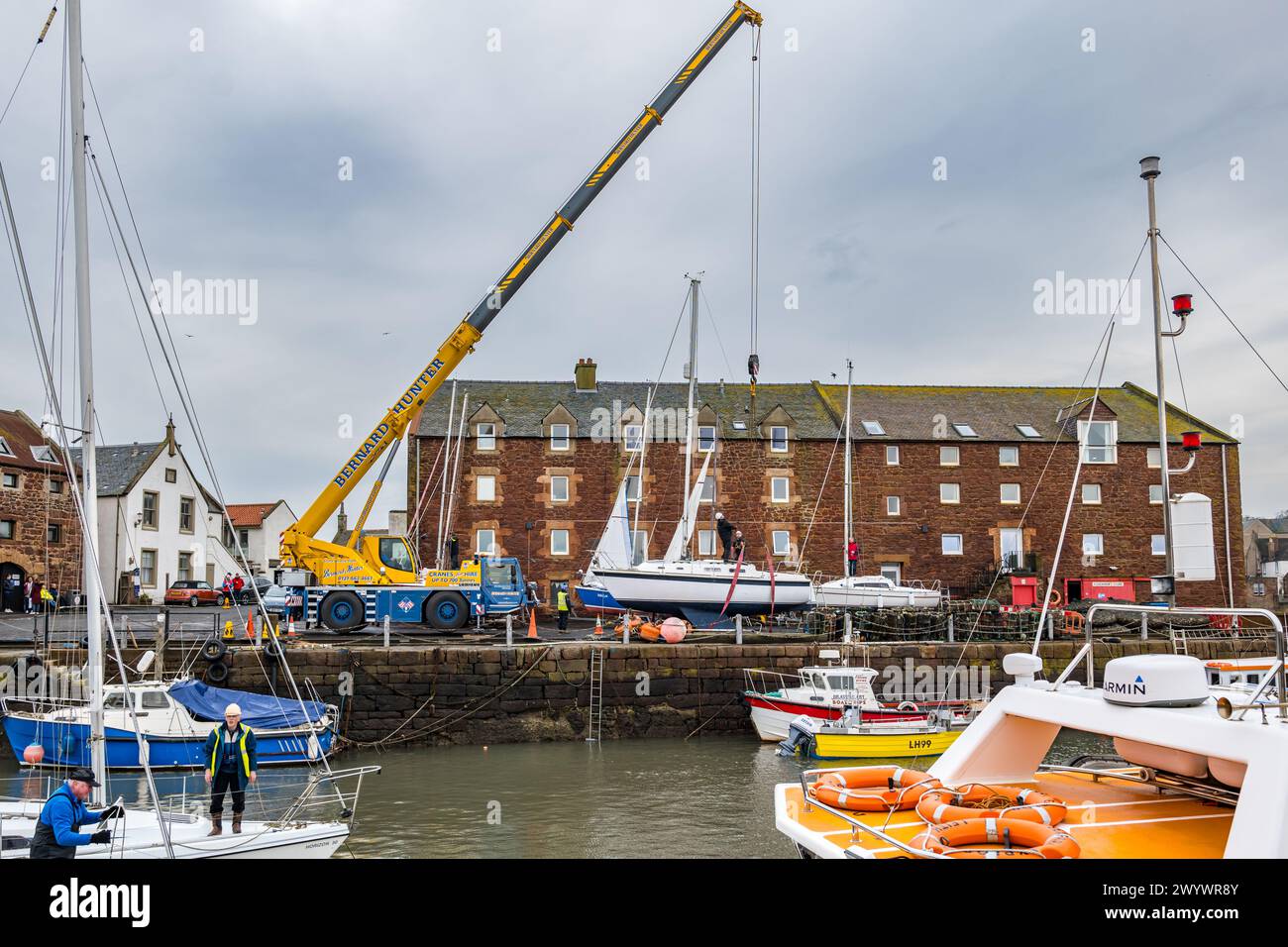 Crane lifting sailing boat into water, North Berwick harbour, East ...