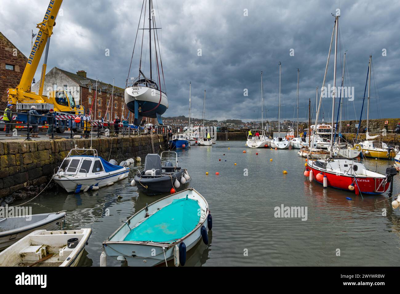 Crane lifting sailing boat into water, North Berwick harbour, East ...