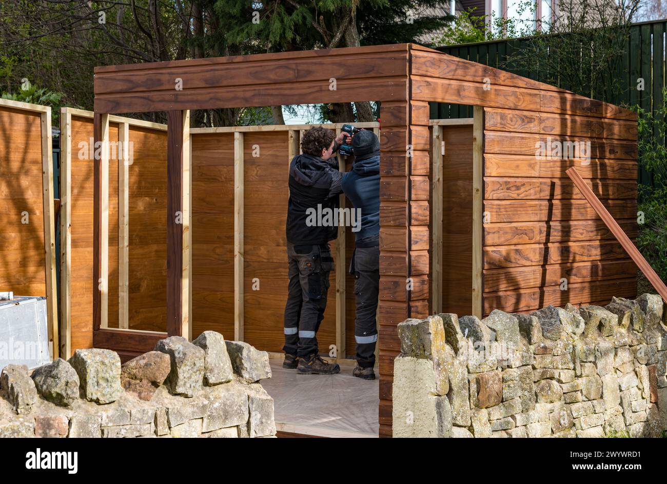 Joiners and workmen erecting the walls of a shed and garden room ...
