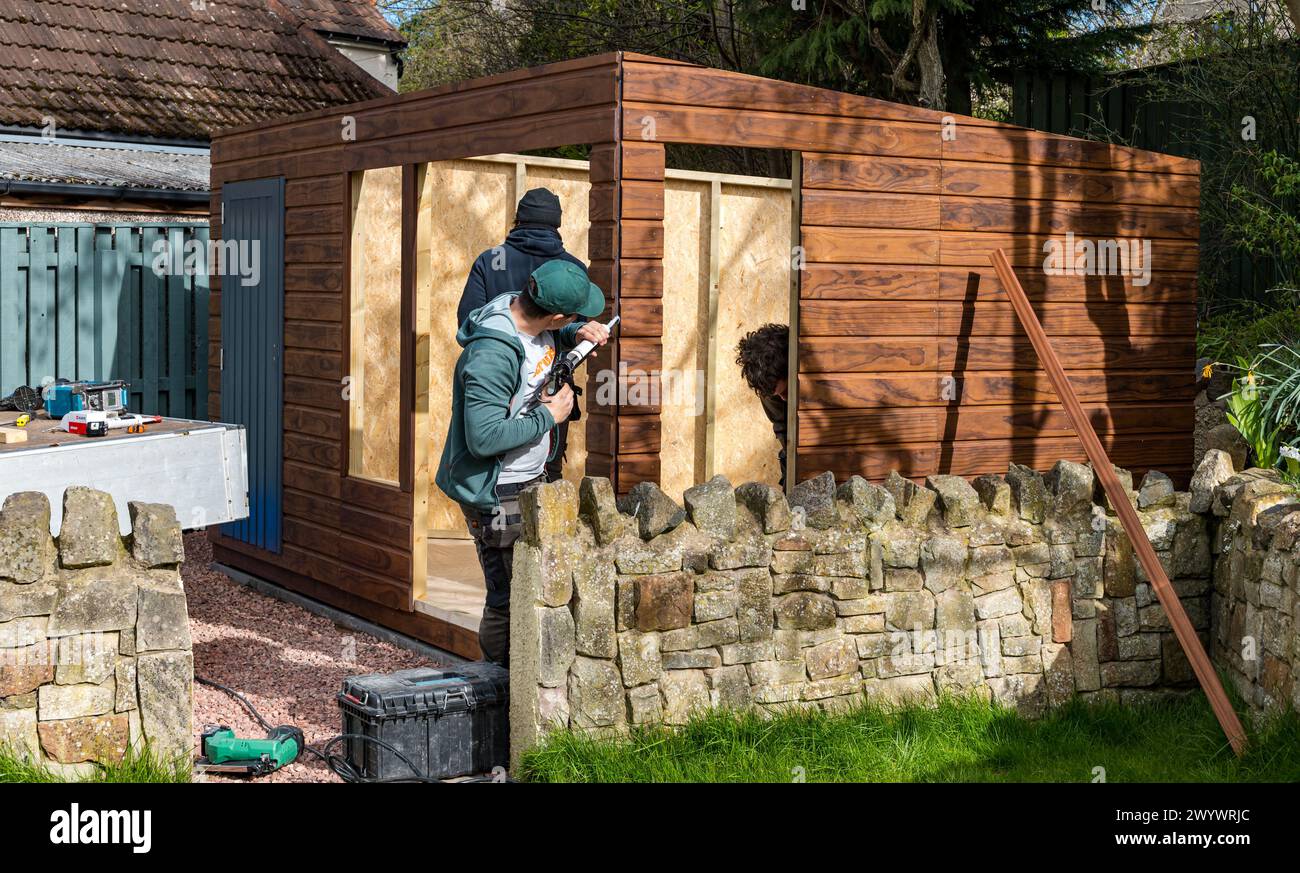 Joiners and workmen erecting the walls of a shed and garden room ...