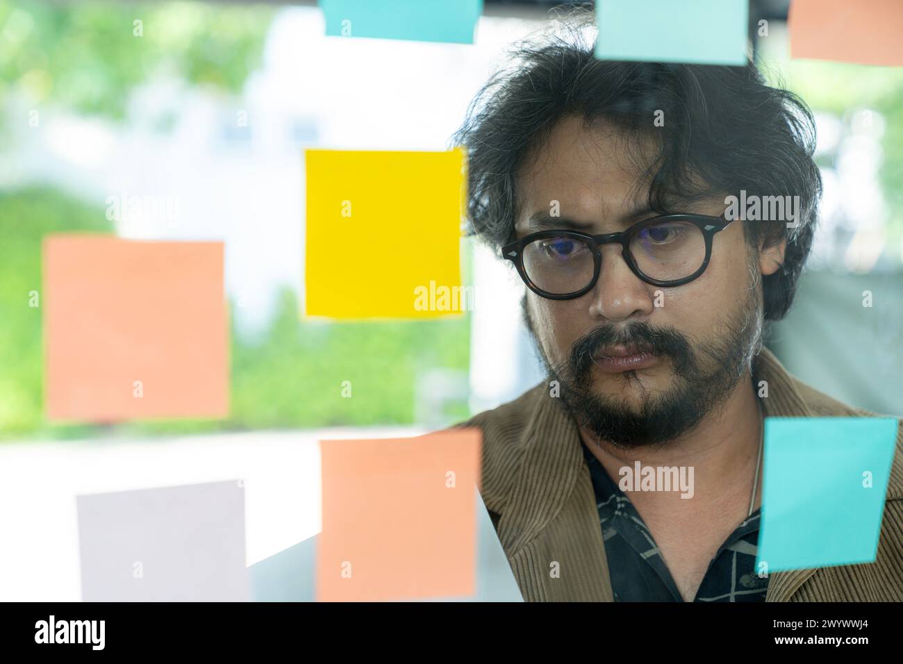 The young businessman has a cheerful expression and is jotting down ...