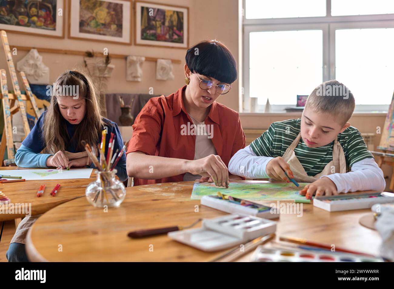Portrait of female teacher assisting children with disability enjoying ...