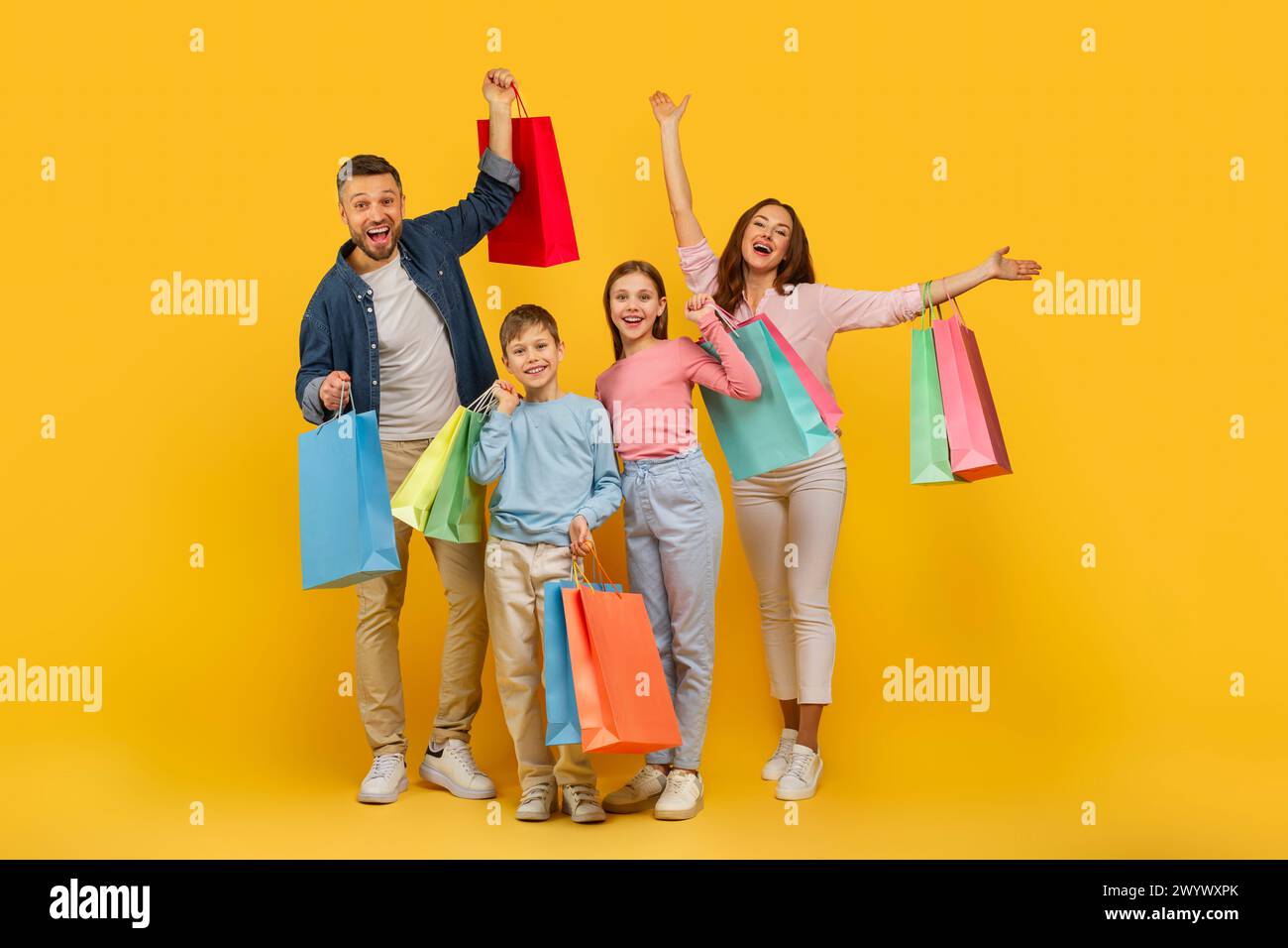 Family celebrating shopping success on yellow background Stock Photo ...