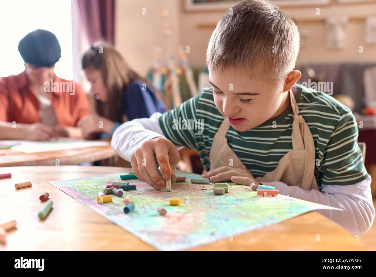 Close up portrait of young boy with Down syndrome drawing picture and ...