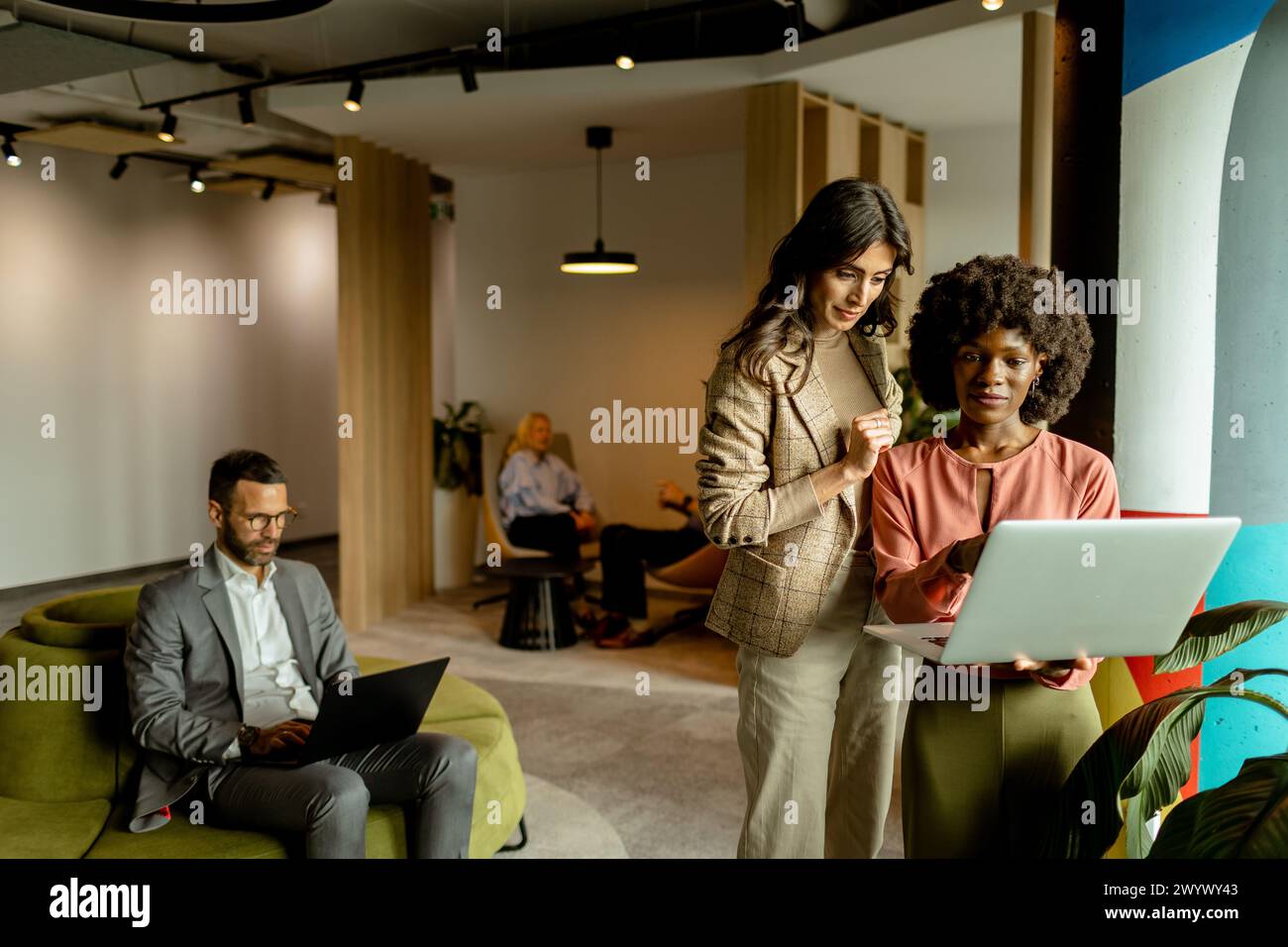 Two professionals engaged in a discussion over a laptop, with a ...