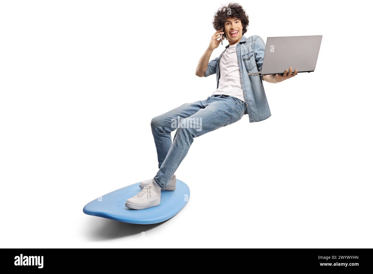 Young man surfing on a surfboard and using a smartphone and holding a ...