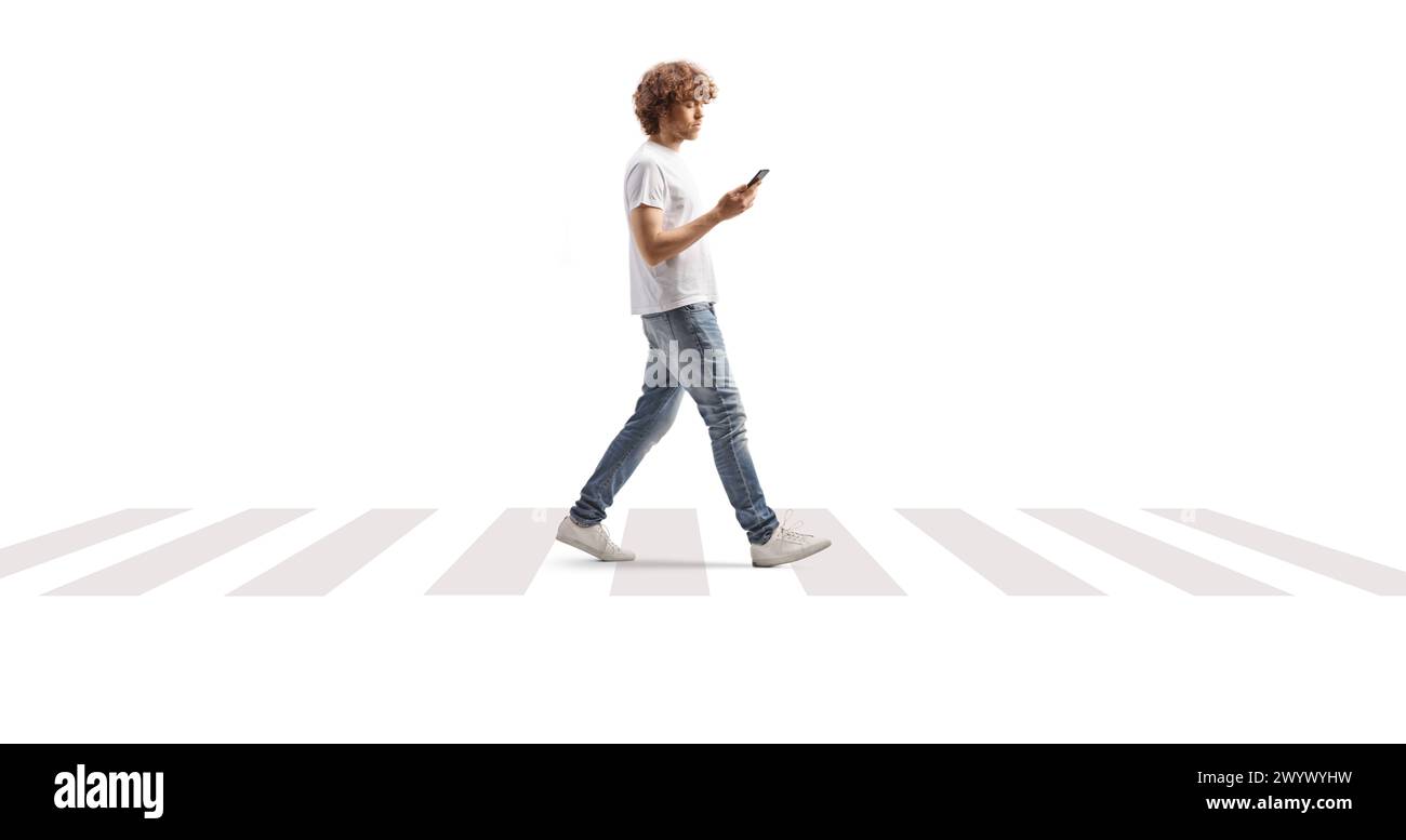 Young man holding a smartphone and crossing a street at pedestrian ...