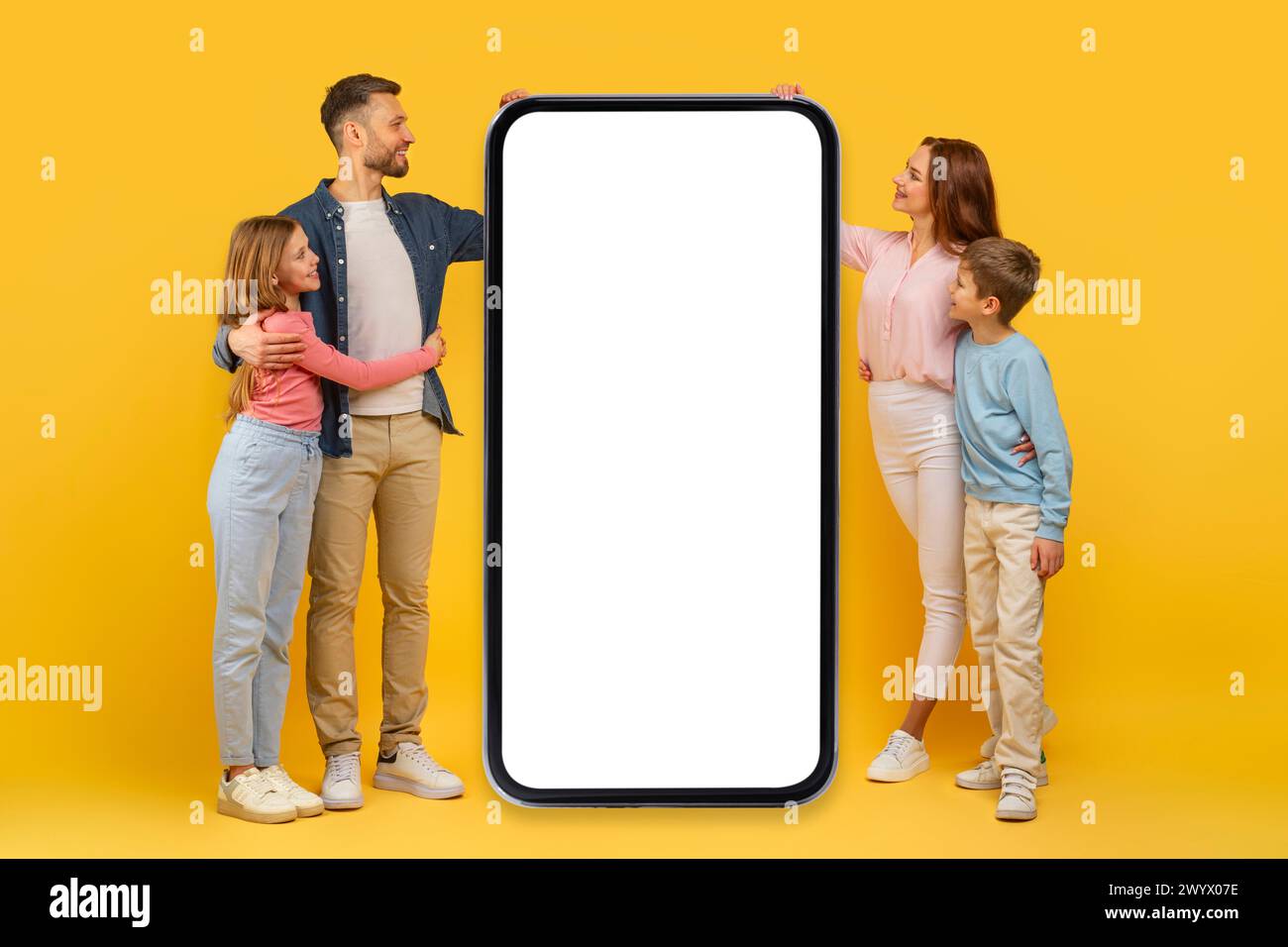 Family looking at big smartphone screen on yellow background Stock ...