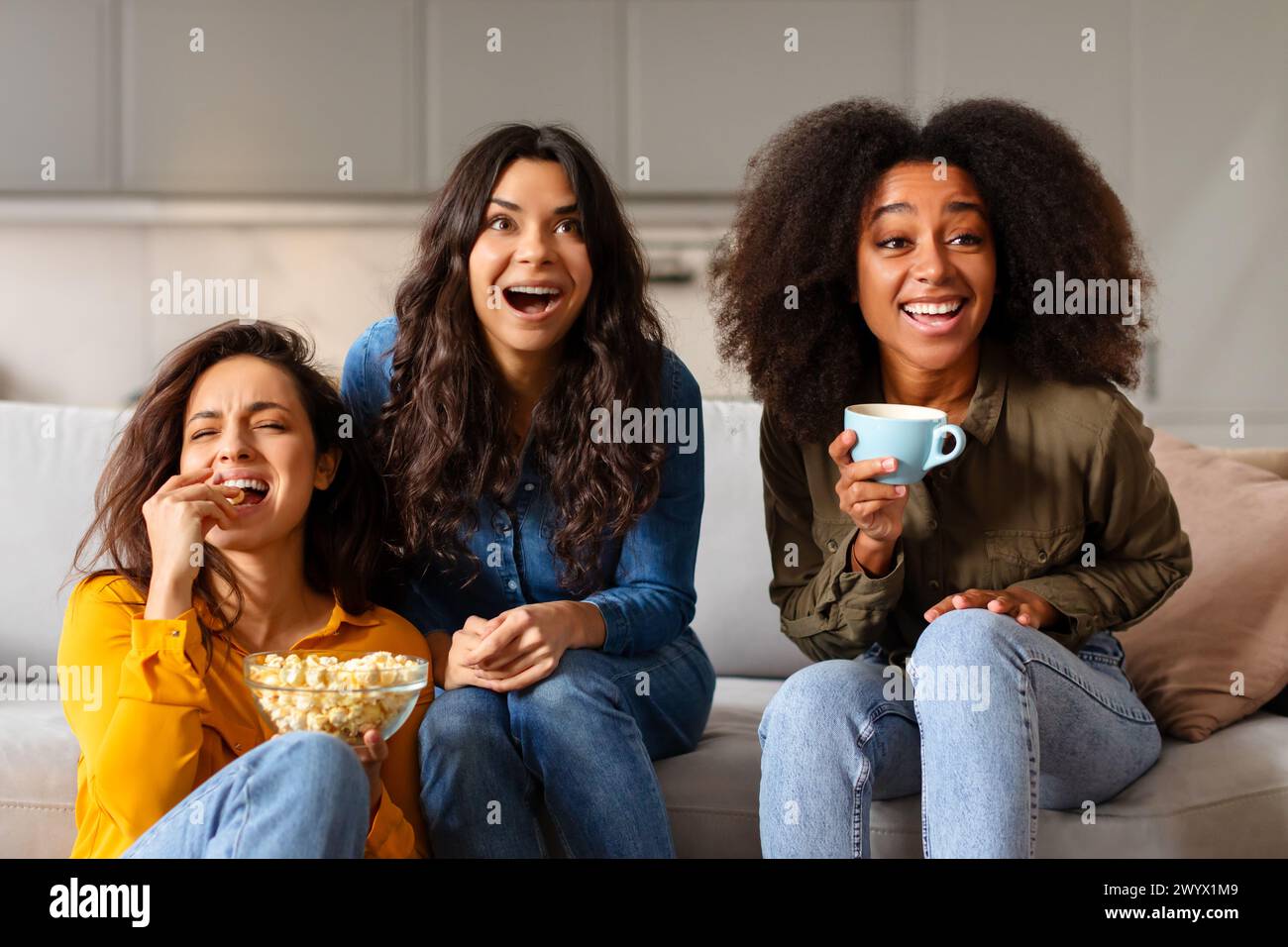 Three friends laughing with coffee and popcorn Stock Photo - Alamy