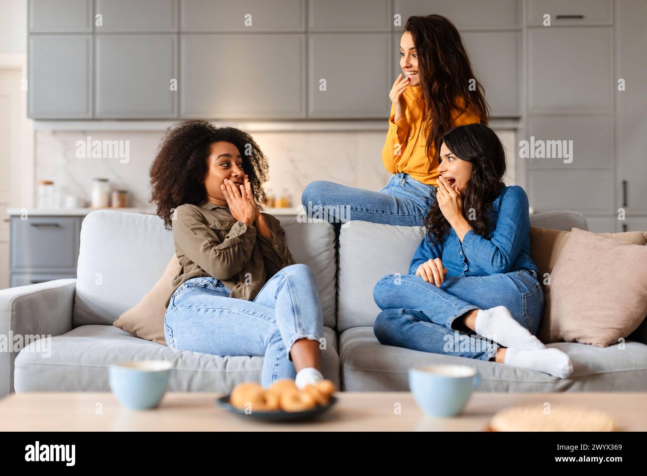 Three women laughing on a couch together Stock Photo - Alamy