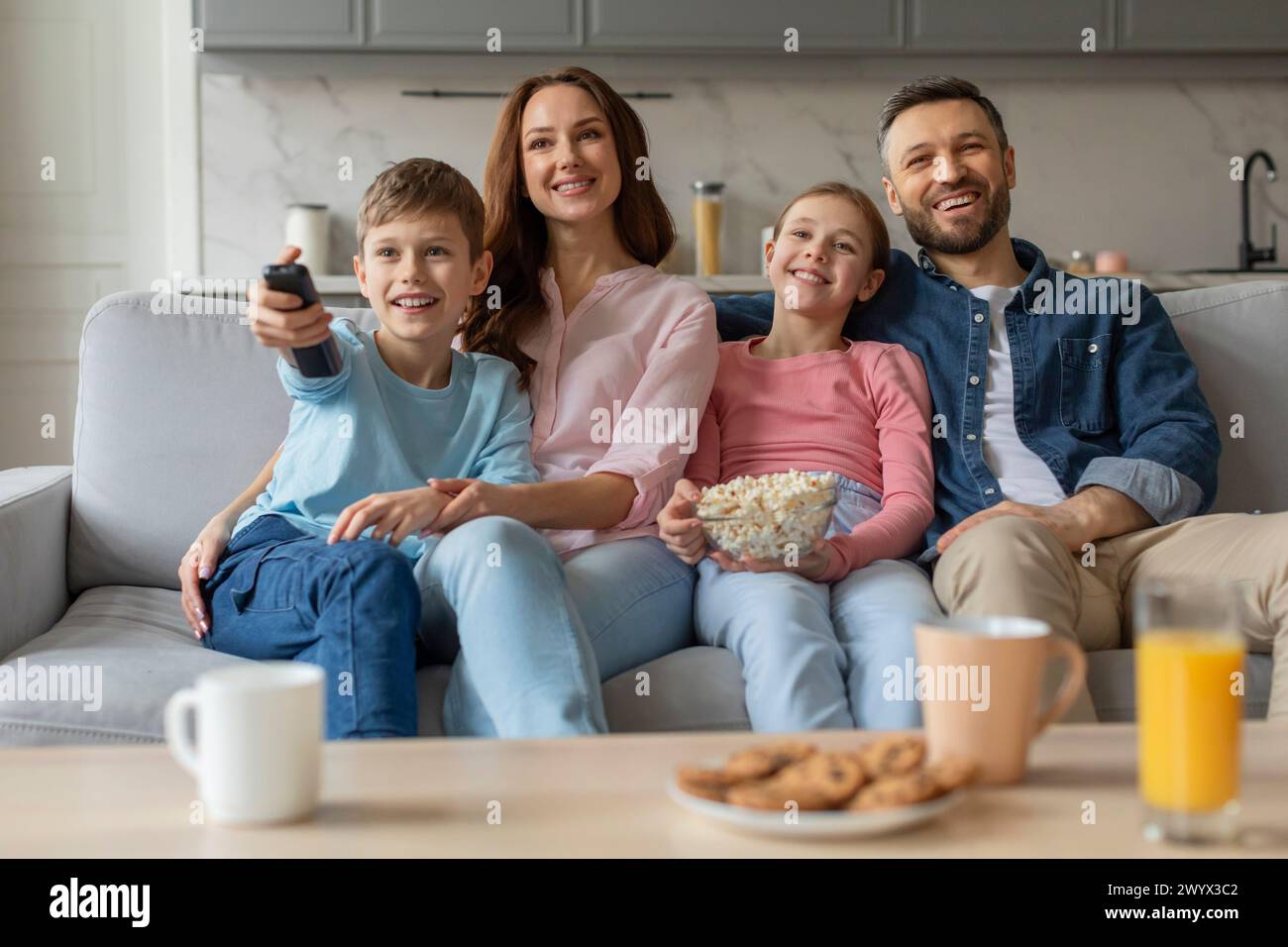 Family watching TV together, smiling joyfully at home Stock Photo - Alamy