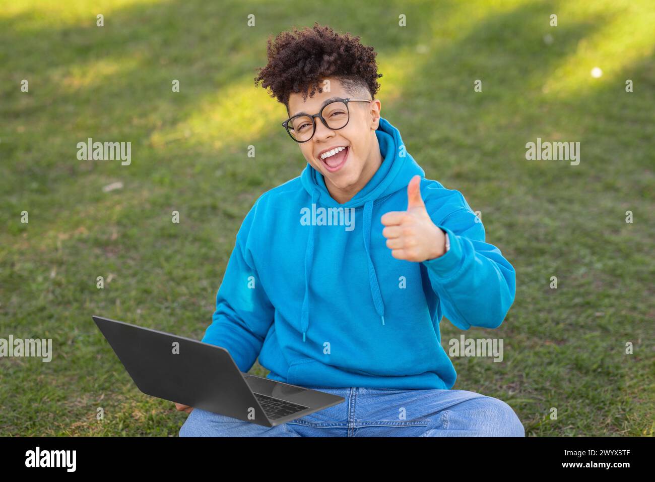 Enthusiastic student giving thumbs up, studying at park Stock Photo - Alamy