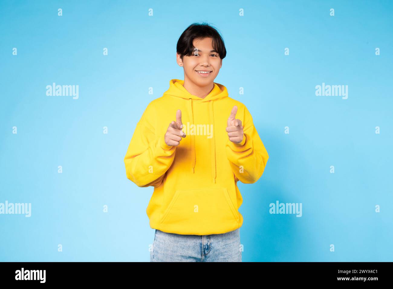 Smiling guy pointing fingers forward blue background Stock Photo - Alamy