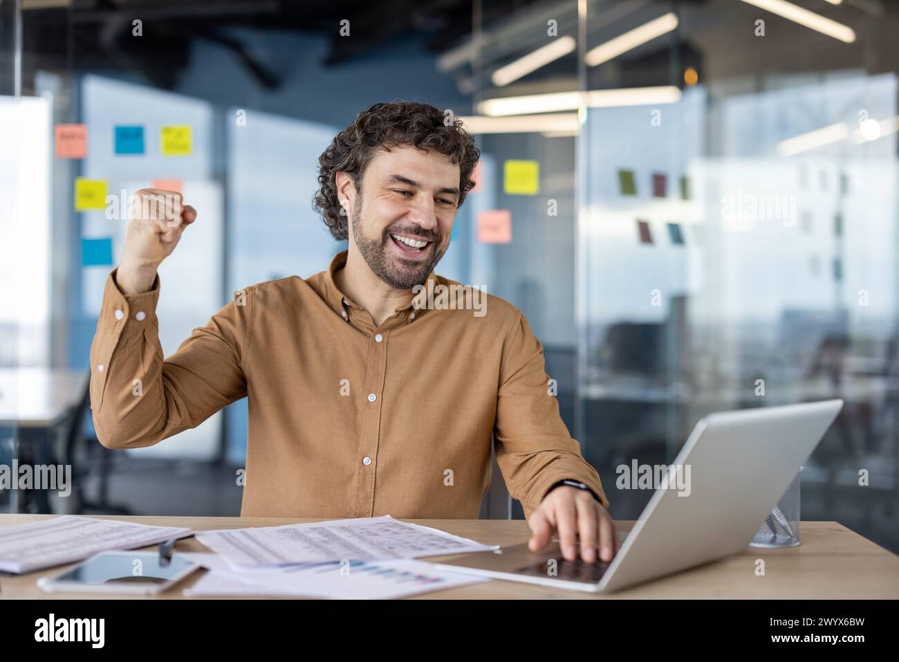 An overjoyed businessman raising his fist in triumph at a well-lit ...