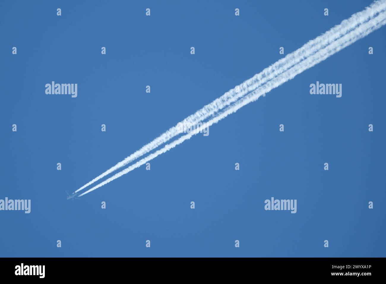 Airplane in the blue sky with contrails Stock Photo - Alamy
