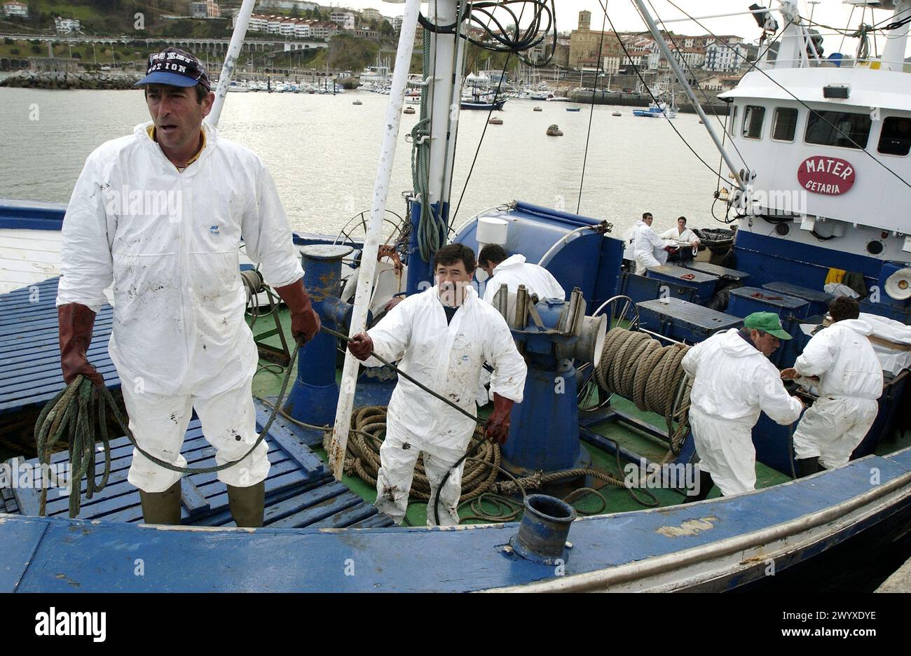 Fishermen dressing protective clothes, gathering the fuel spill ...