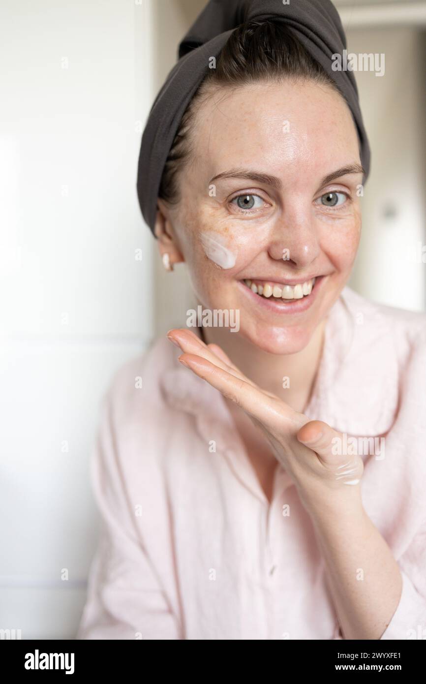 Woman looking at camera, smiling and showing cosmetic cream smear on ...