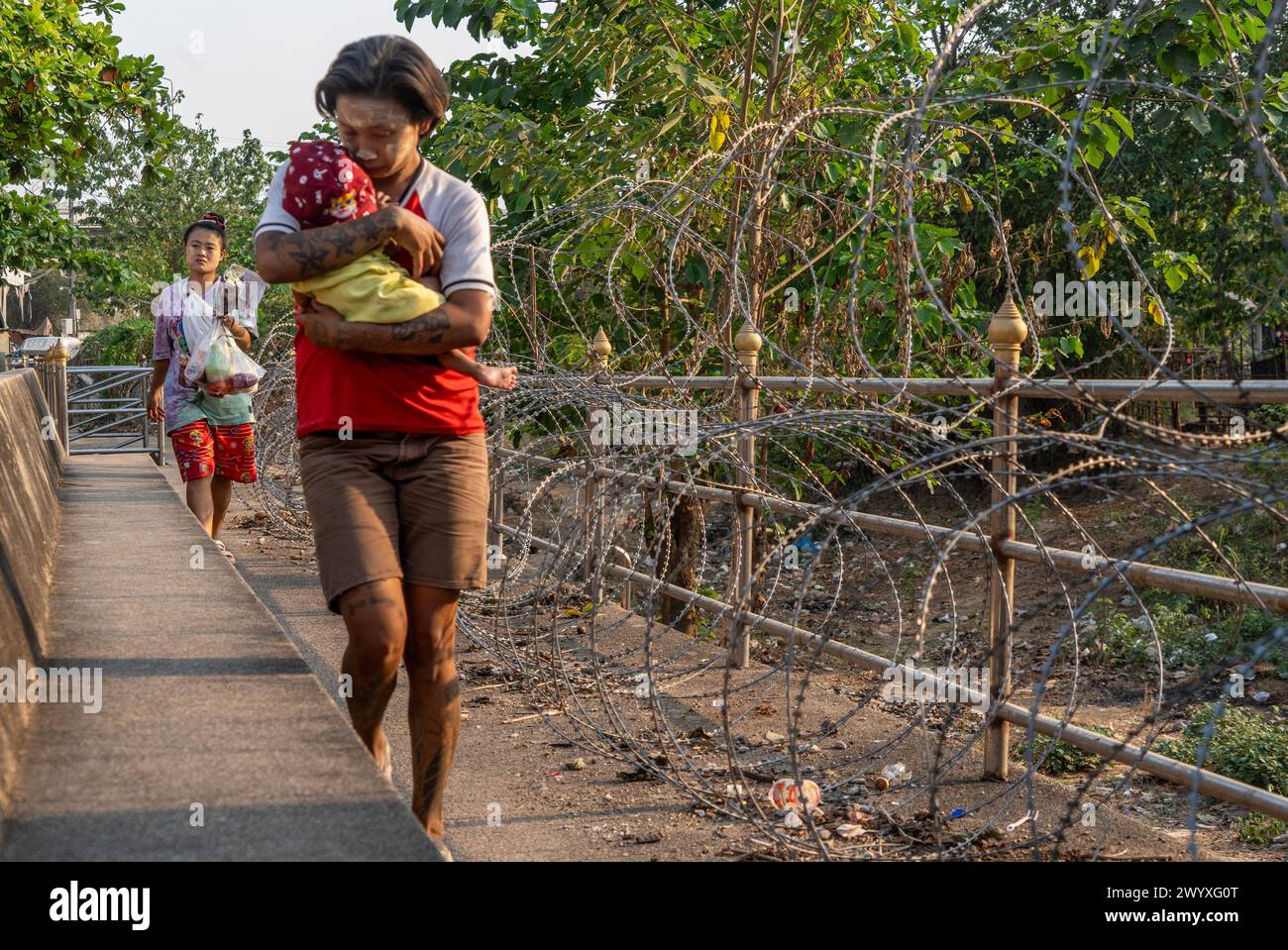 Visitors, traders and illegal Burmese immigrants walk by barbed wire at the Thai side of the ...
