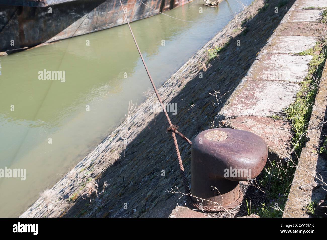 Old metal dock mooring pole with steel rope for securing river bulk ...