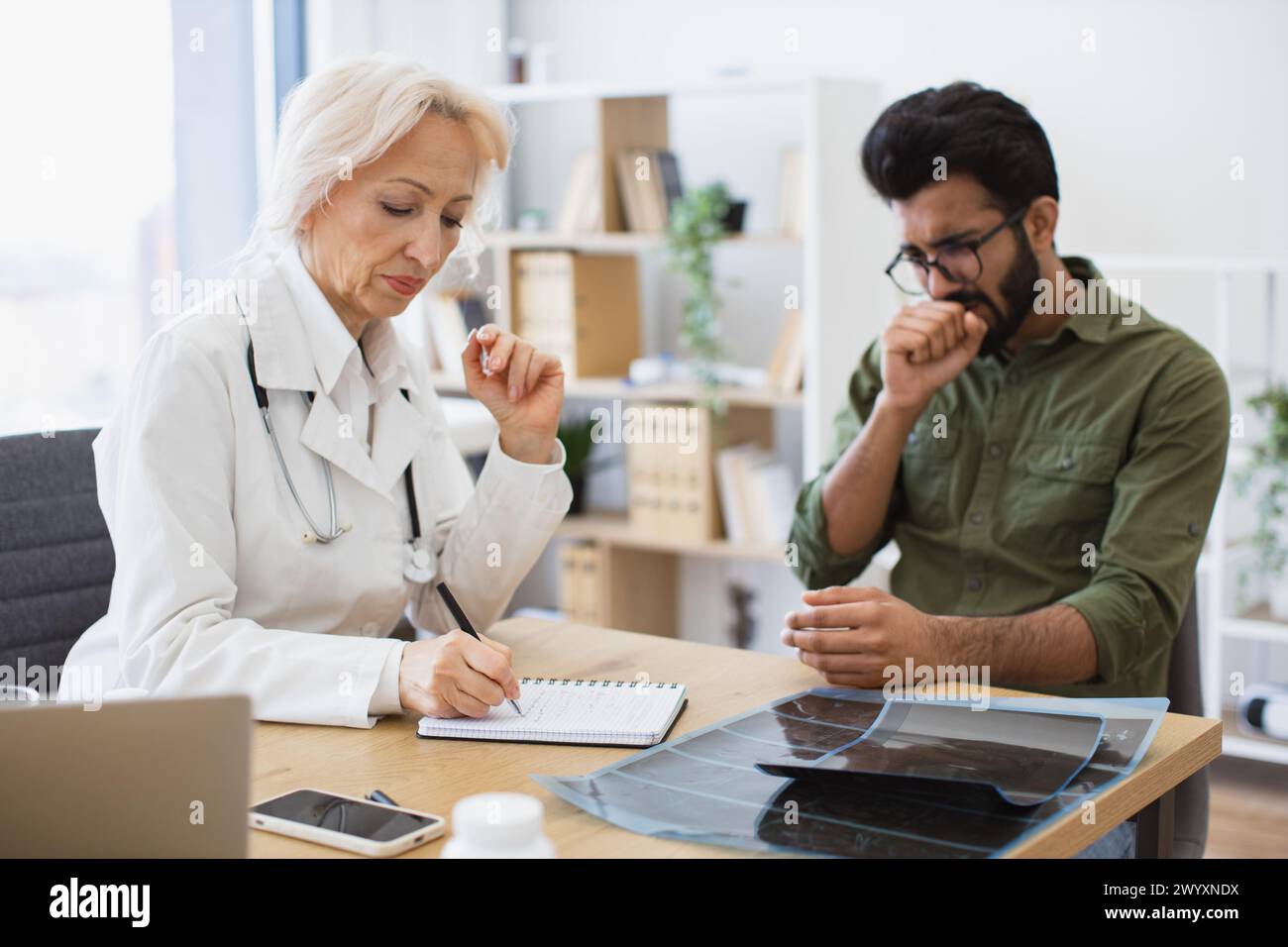 Doctor discussing health issues and prescribes medication for treatment ...