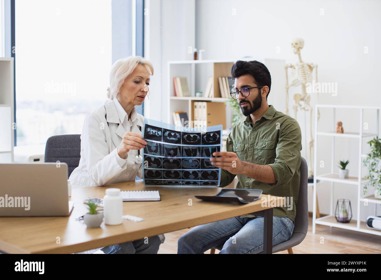 Skilled radiologist in white uniform explaining visible changes on x ...